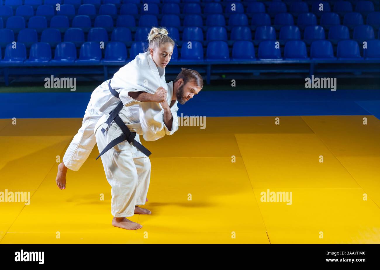 Martial arts. Sparing Portners. Sport man and woman in white kimono train judo throws and ...