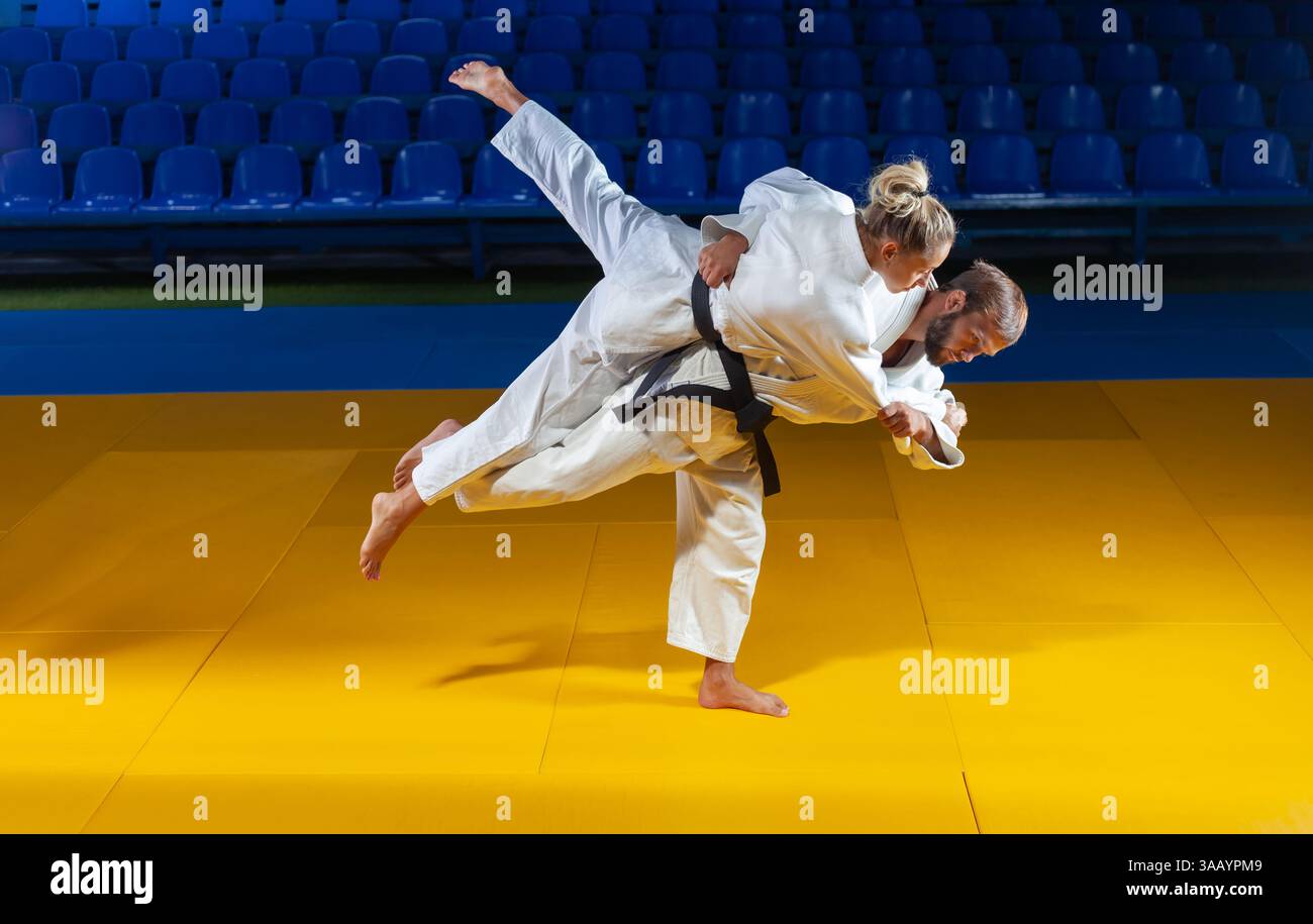 Martial arts. Sparing Portners. Sport man and woman in white kimono train judo throws and ...