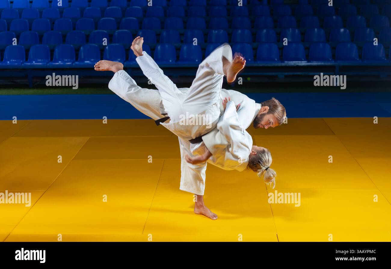 Martial arts. Sparing Portners. Sport man and woman in white kimono train judo throws and ...