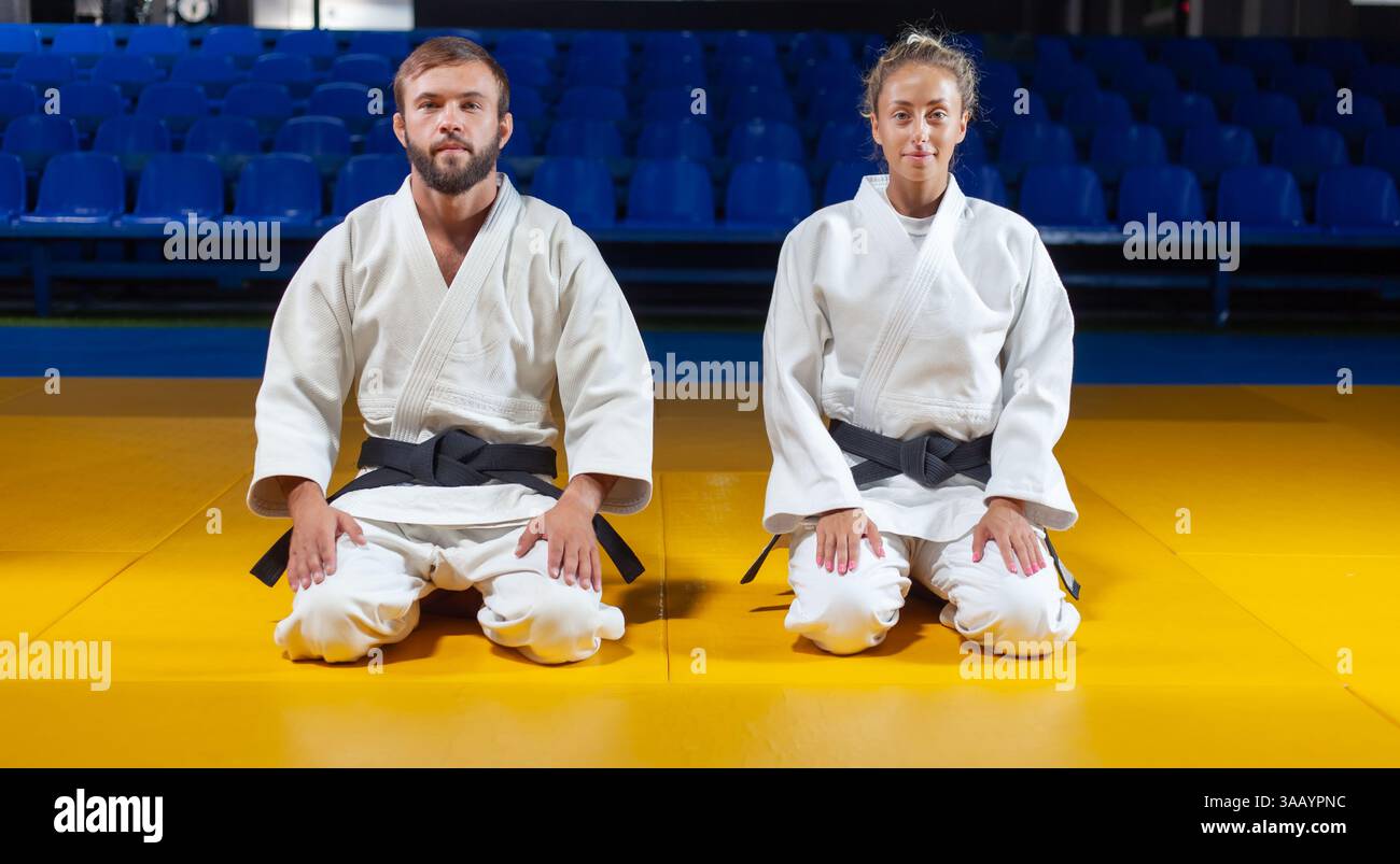 Man and woman in white kimono with a black belt sit on the floor and ...