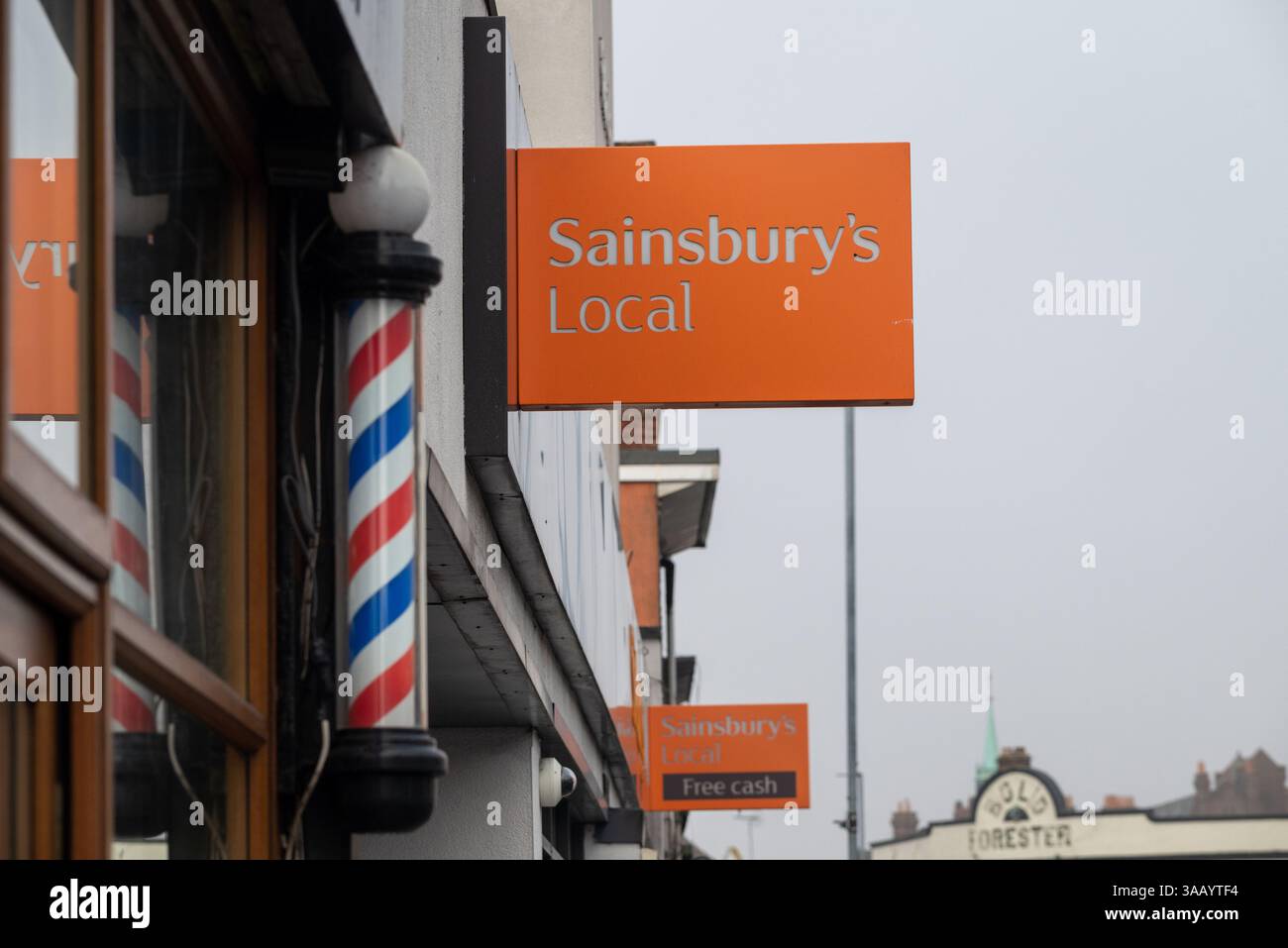 Bright orange exterior sign for a Sainsbury's local store. March 2025 ...