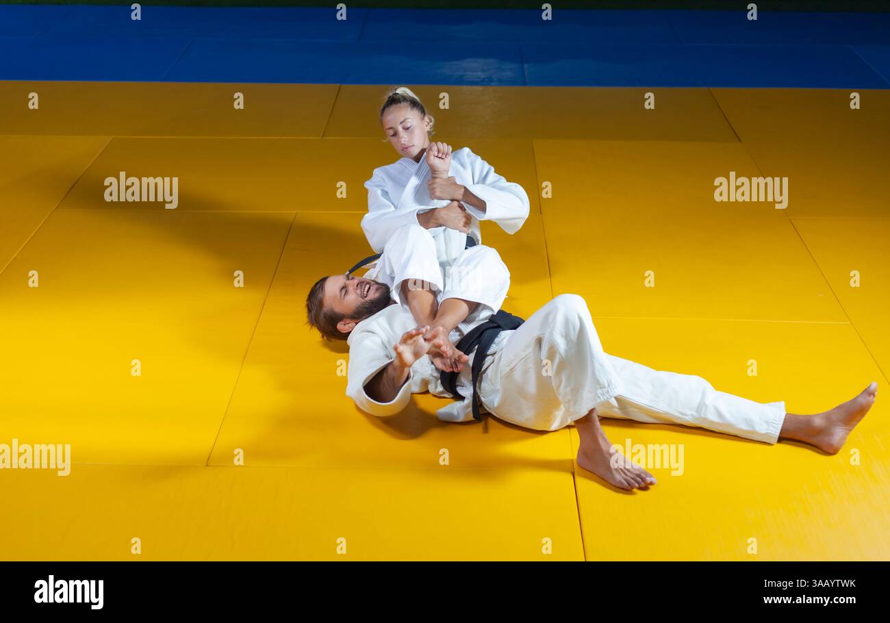 Martial arts. Sparing Portners. Sport man and woman in white kimono train judo throws and ...