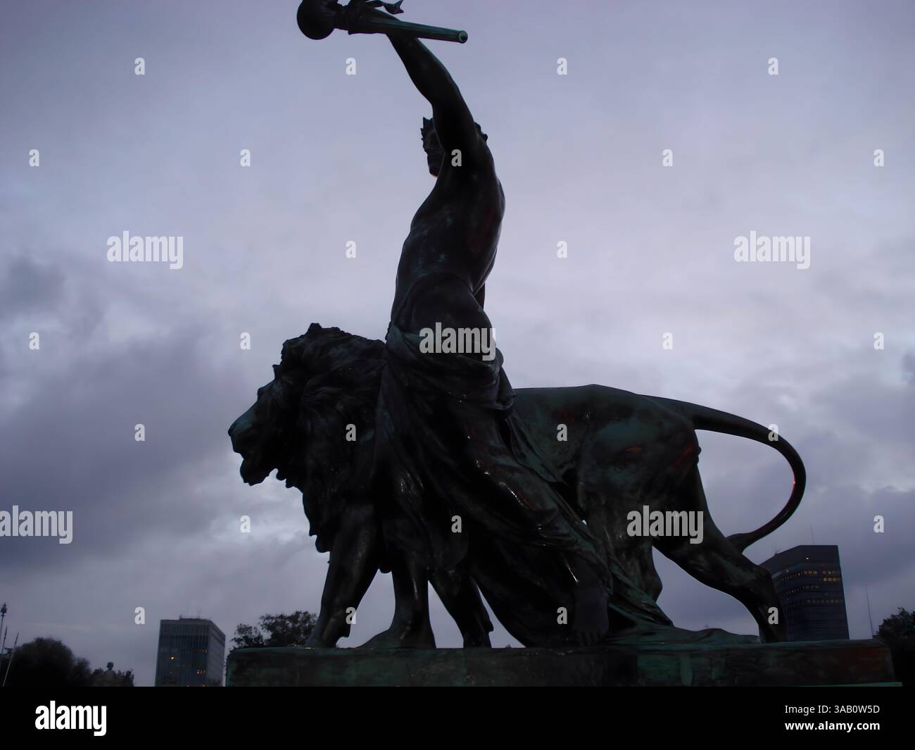 A bronze statue of a muscular figure holding a sword aloft, standing on ...