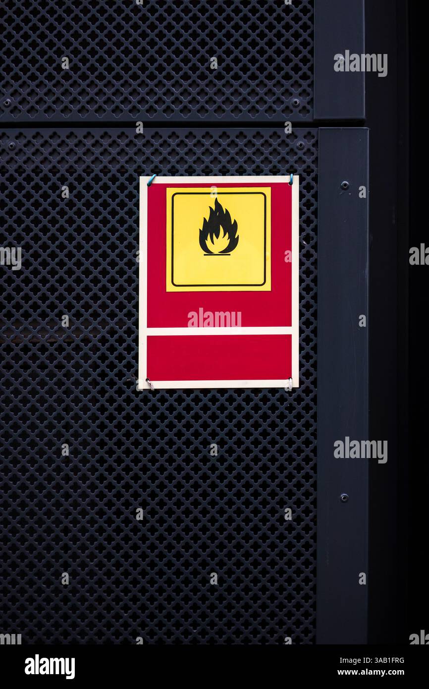 Cautionary fire warning sign attached to a black metallic grill, close ...