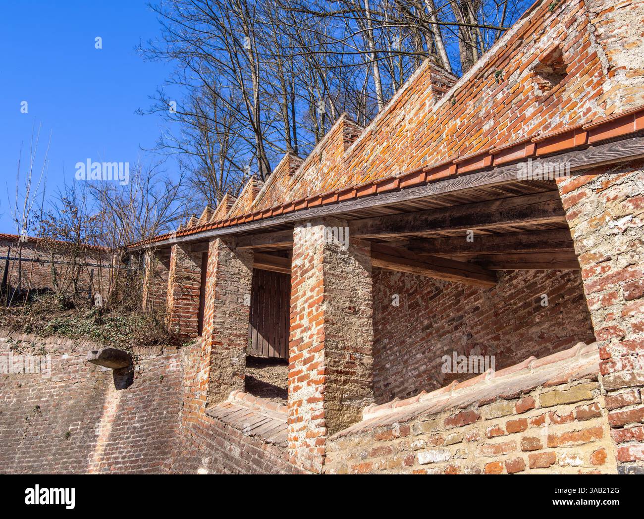 A historic brick wall with a sloped roof, The building features exposed ...