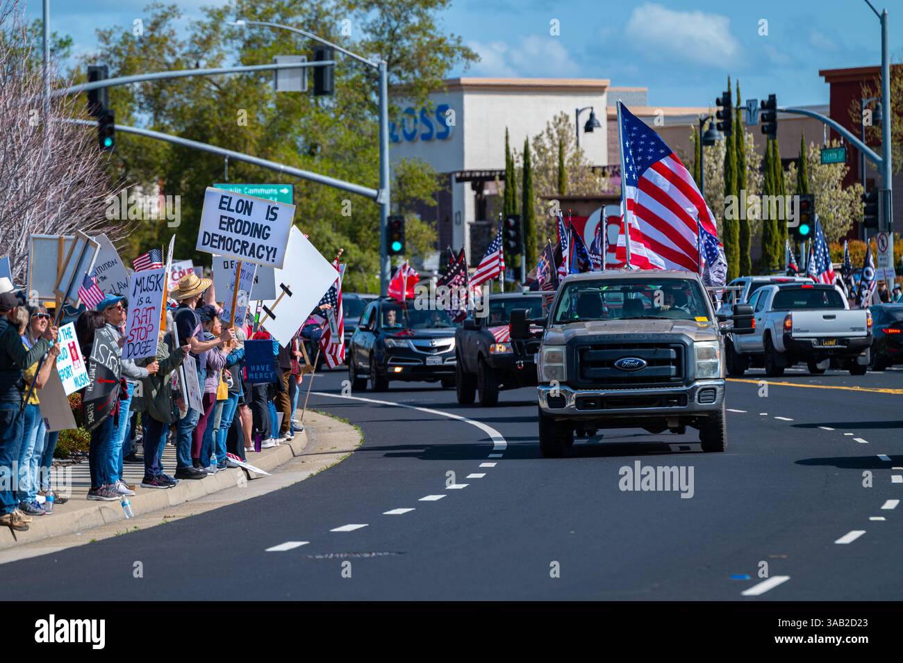 A truck caravan with U.S. and other flags drive past anti-Elon Musk ...