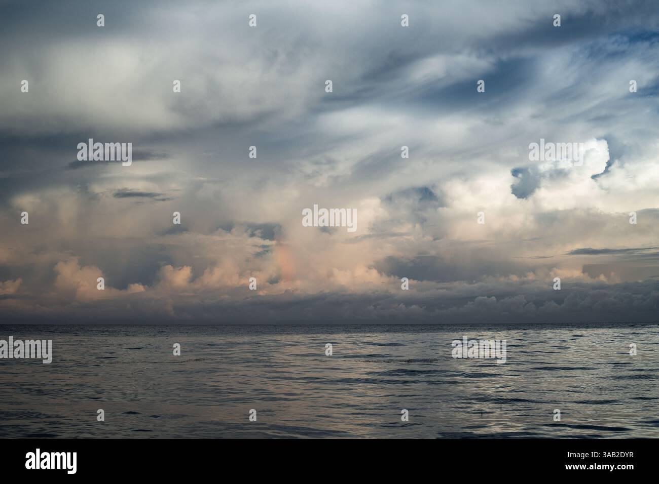 A tranquil ocean surface stretches beneath a dramatic cloudscape at ...