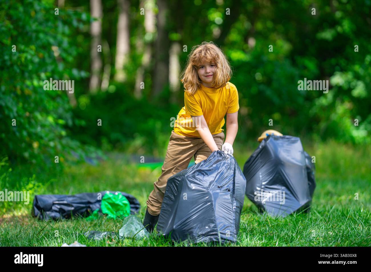 Kid in rubber gloves with trash bag clean up garbage on forest outdoor ...