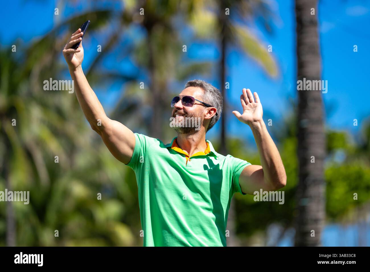 Tourist takes a selfie near palm tree. Man traveler captures a selfie ...