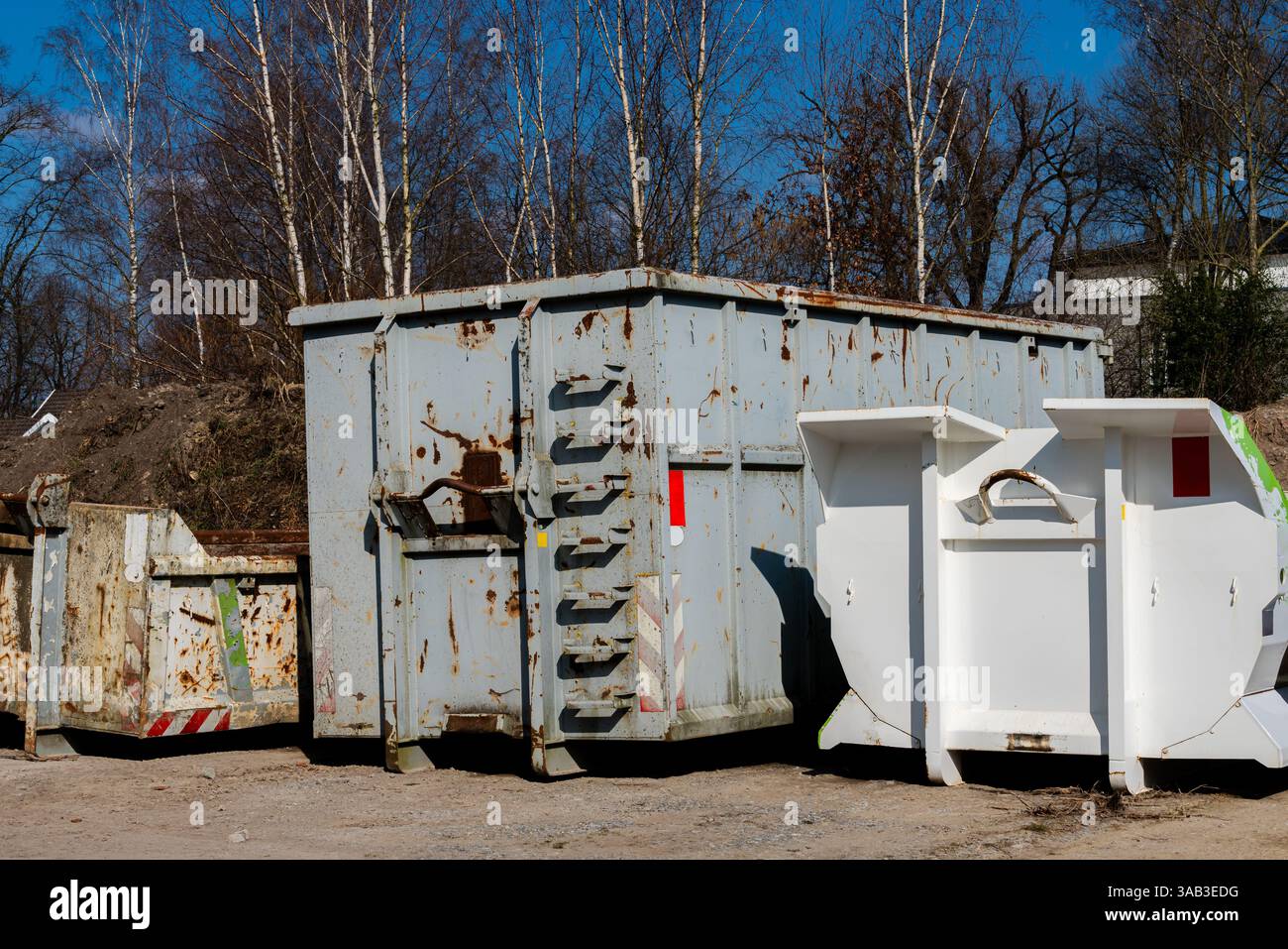 Several large, rusted metal containers sit in an industrial area under ...