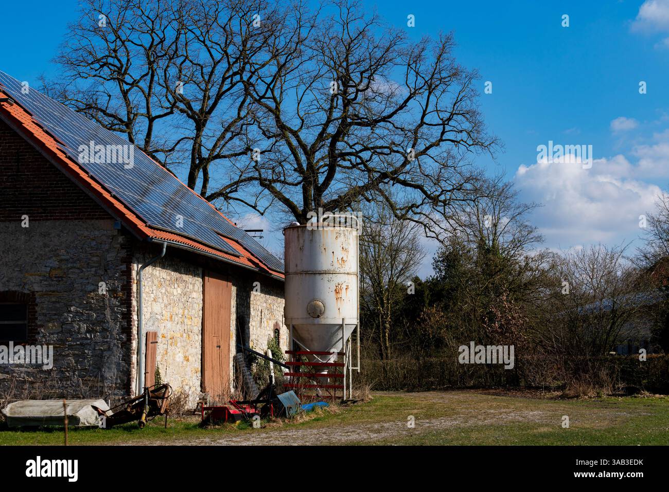 A rustic barn with a red door stands against a clear blue sky ...