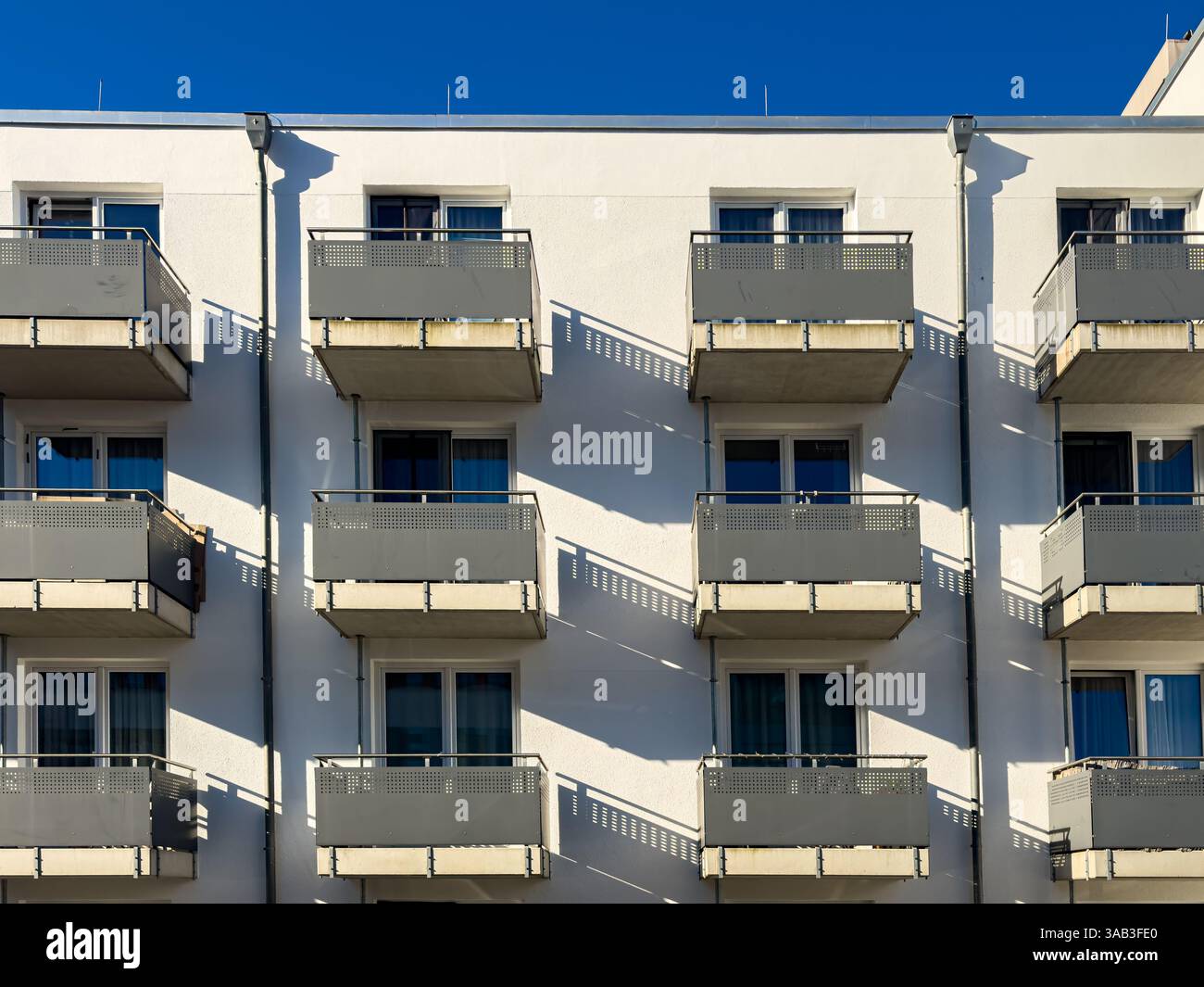 A modern apartment building showcases multiple white balconies. Bright ...