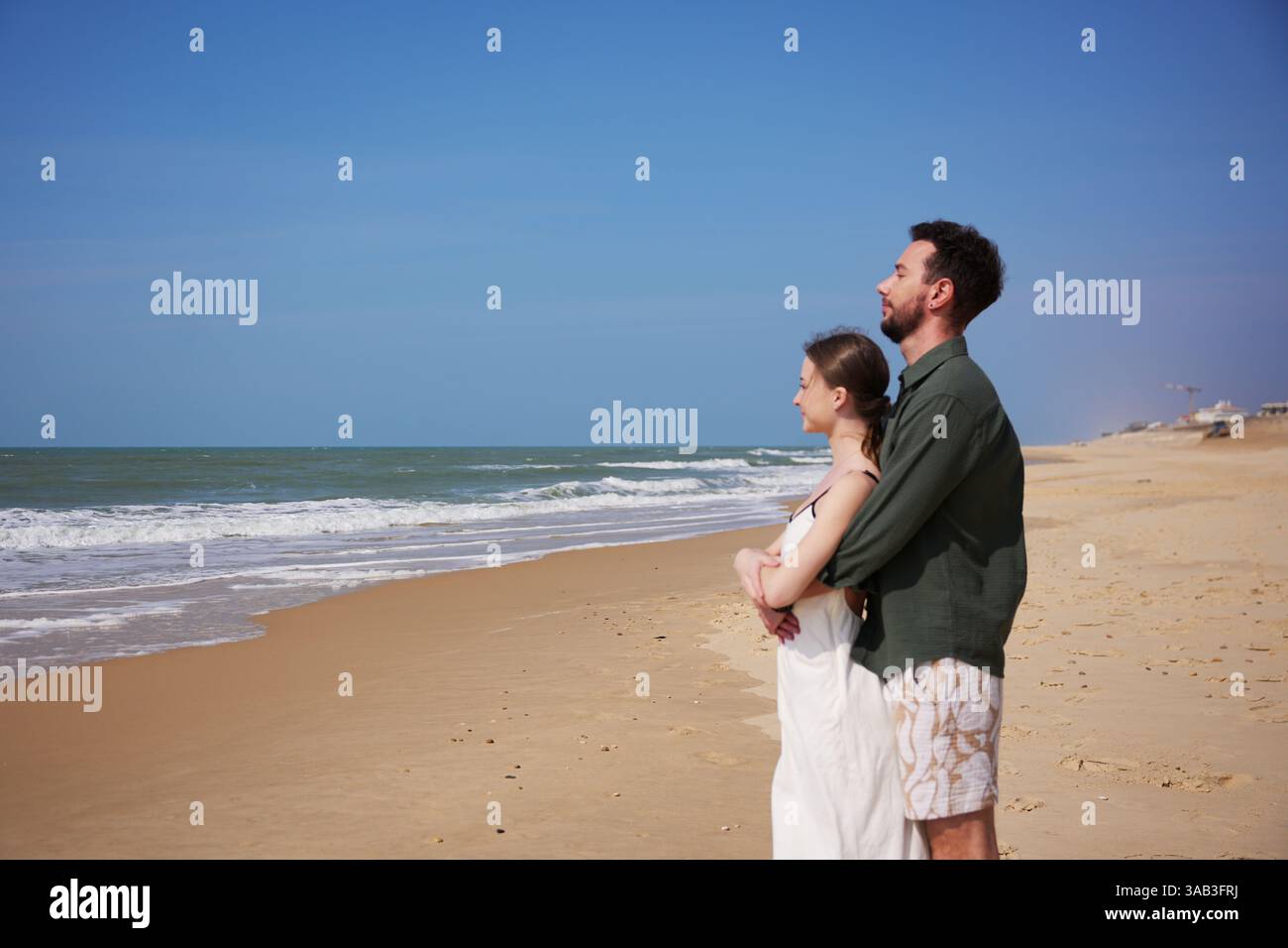 A joyful young couple shares a romantic moment at the seaside as the ...