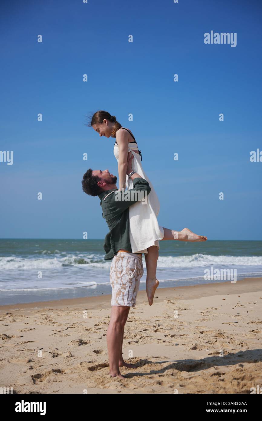 A joyful young couple shares a romantic moment at the seaside as the ...