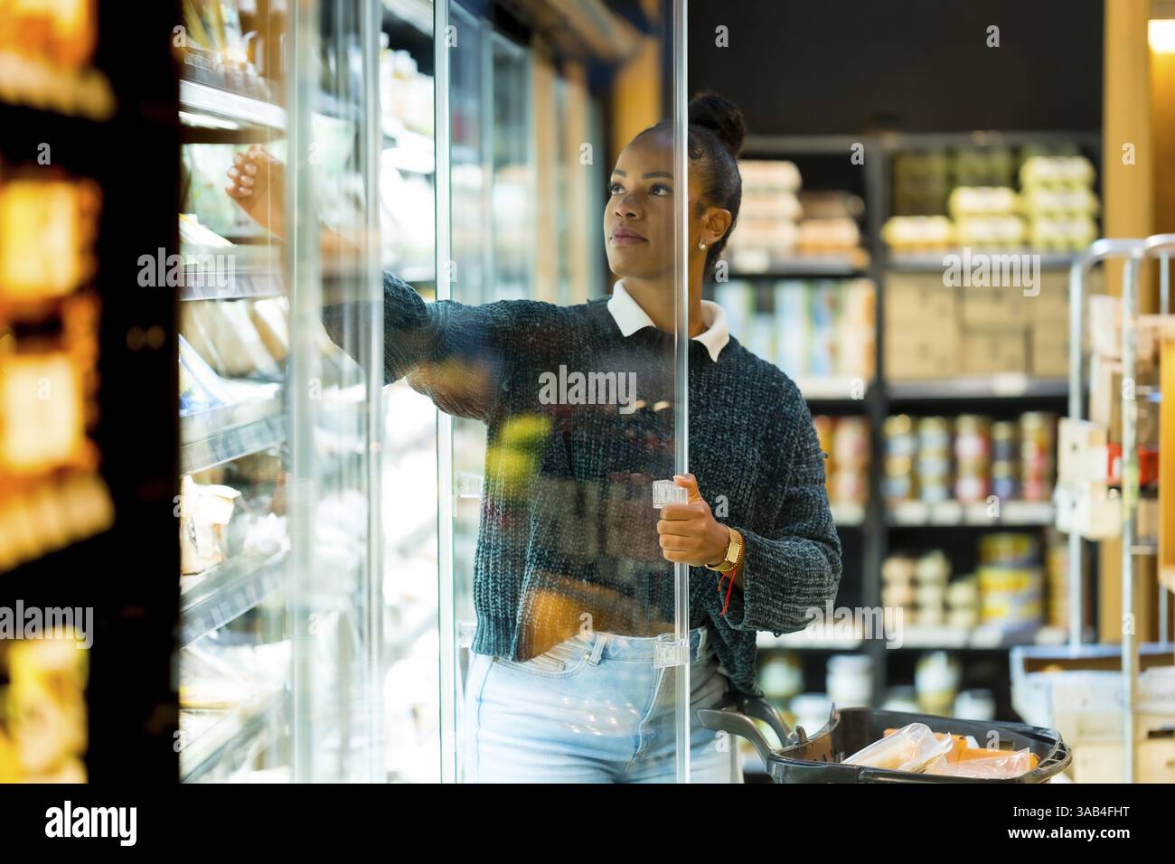 Customer selecting groceries from refrigerated section in a supermarket ...