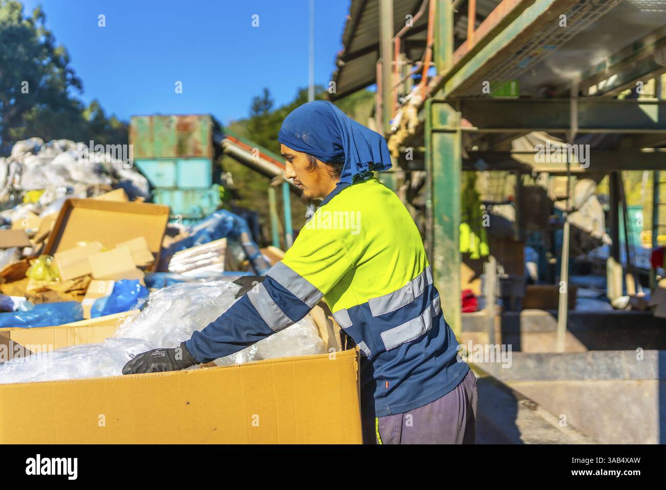 Side view photo of a latin male worker separating materials outside a recycling plant under the ...