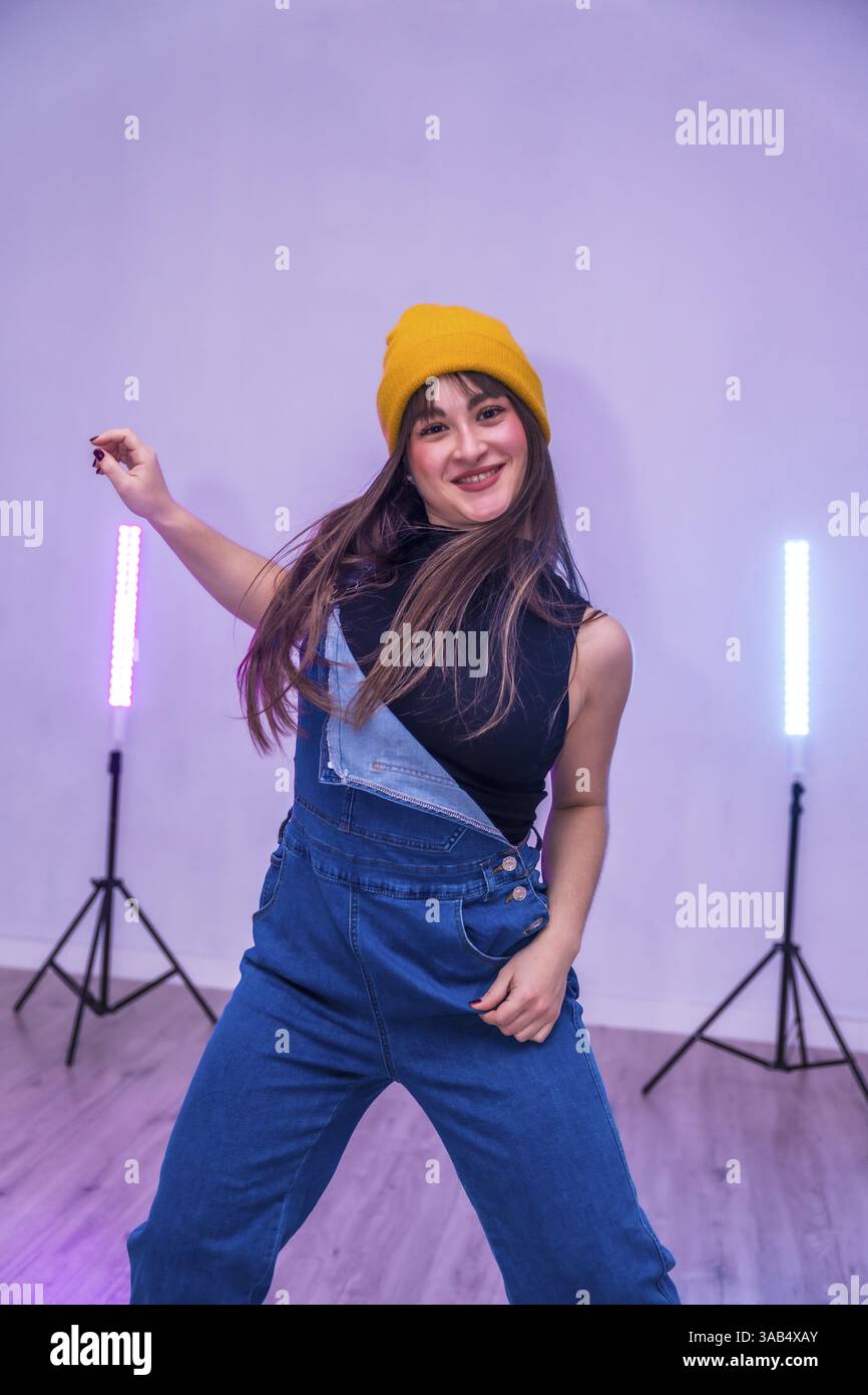 Female dancer wearing a yellow beanie and denim overalls is dancing in ...