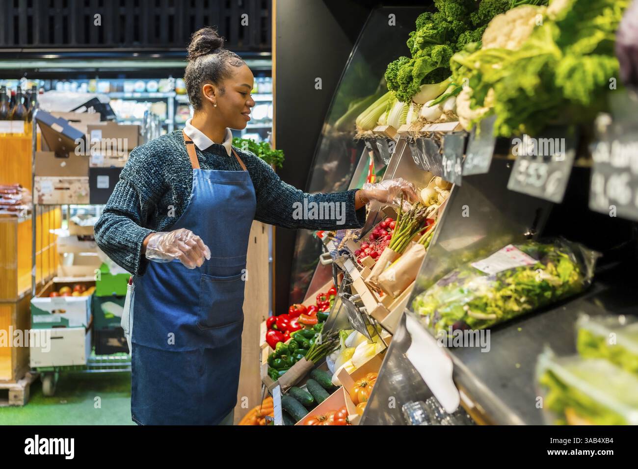 Grocery store employee wearing gloves arranging organic vegetables on ...