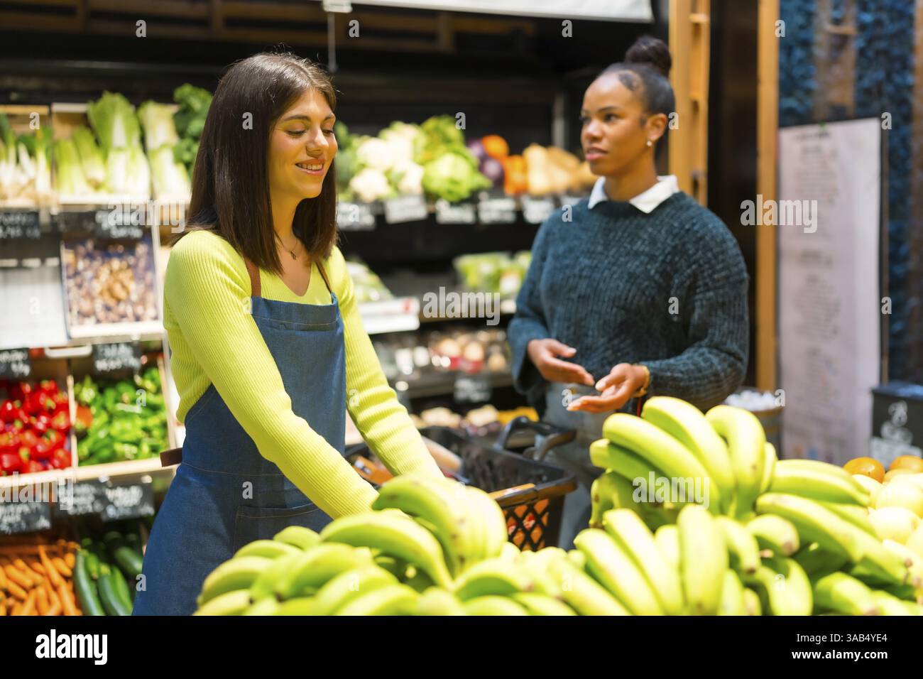 Greengrocer arranging fresh bananas on the counter while talking with a ...