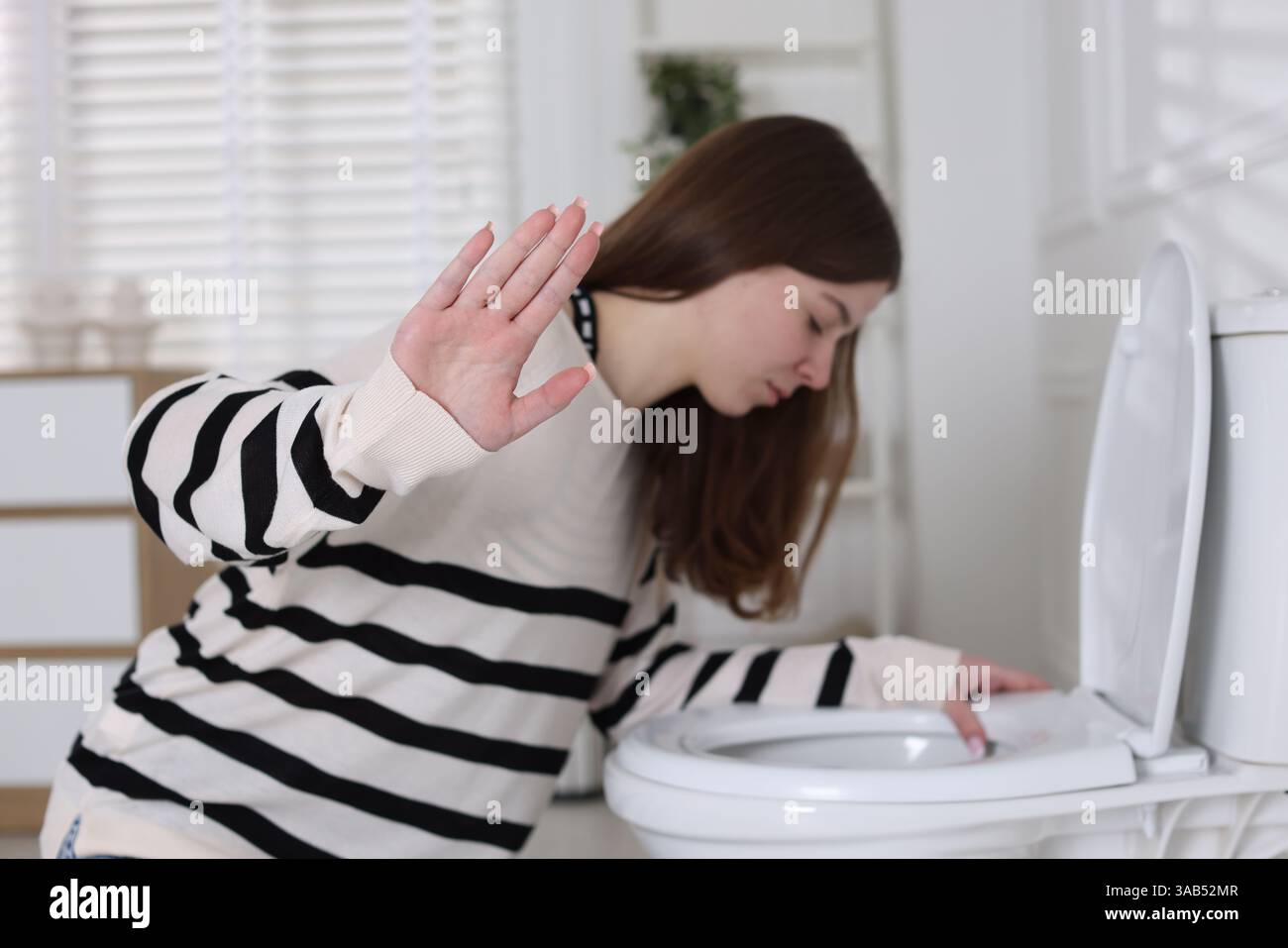 Teenage girl suffering from nausea over toilet bowl showing stop ...