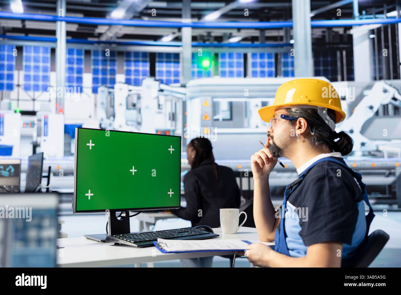 Technician in photovoltaics factory using green screen PC to improve solar panels assembly ...