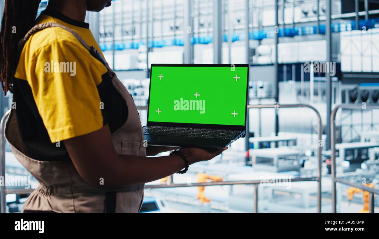Worker using green screen laptop in smart factory, collecting and ...