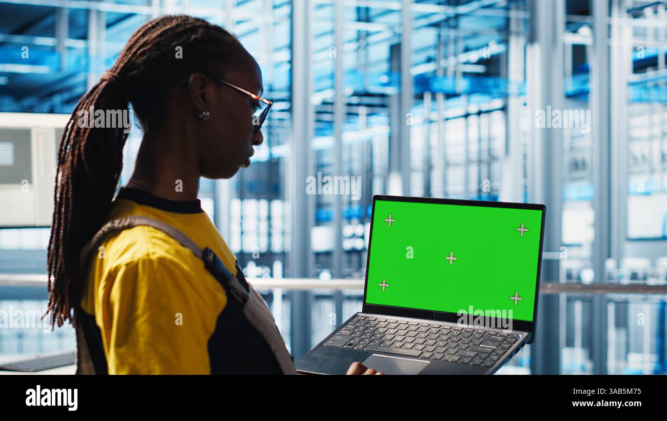 Worker using green screen laptop in smart factory, collecting and analyzing data. Expert using ...