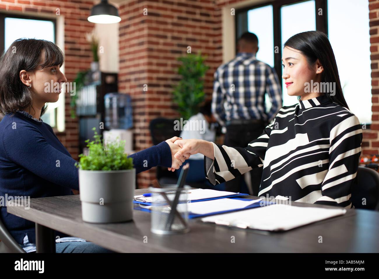 Human resources employee welcomes a white woman, shaking her hand at ...