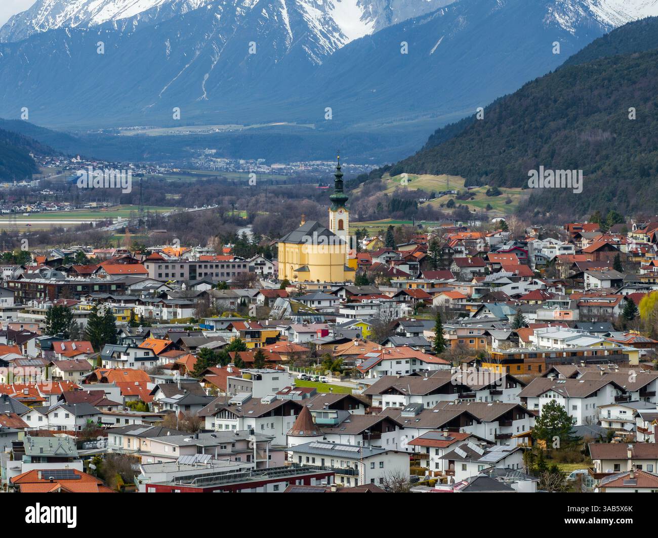 Austrian Town with Yellow Church and Alpine Mountain Backdrop Stock ...