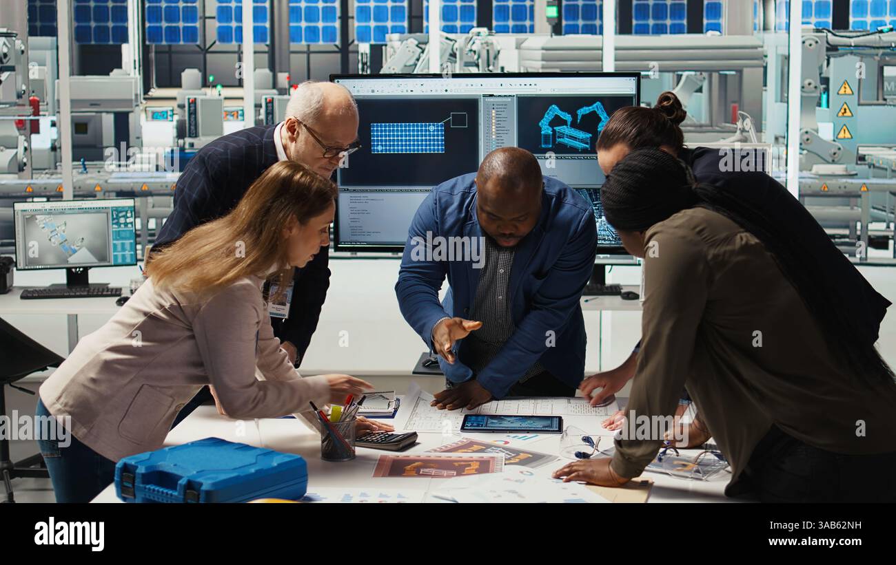 Factory engineers study detailed schematics of solar panel assembly ...