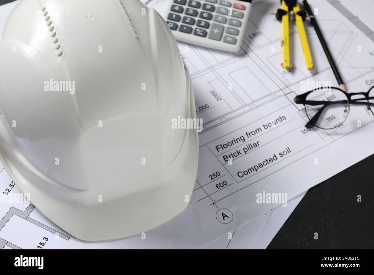 Different engineering drawings, hard hat, pencil, divider, glasses and ...