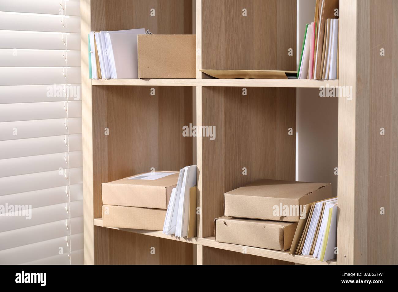 Different paper envelopes and parcels on wooden shelves in post office ...