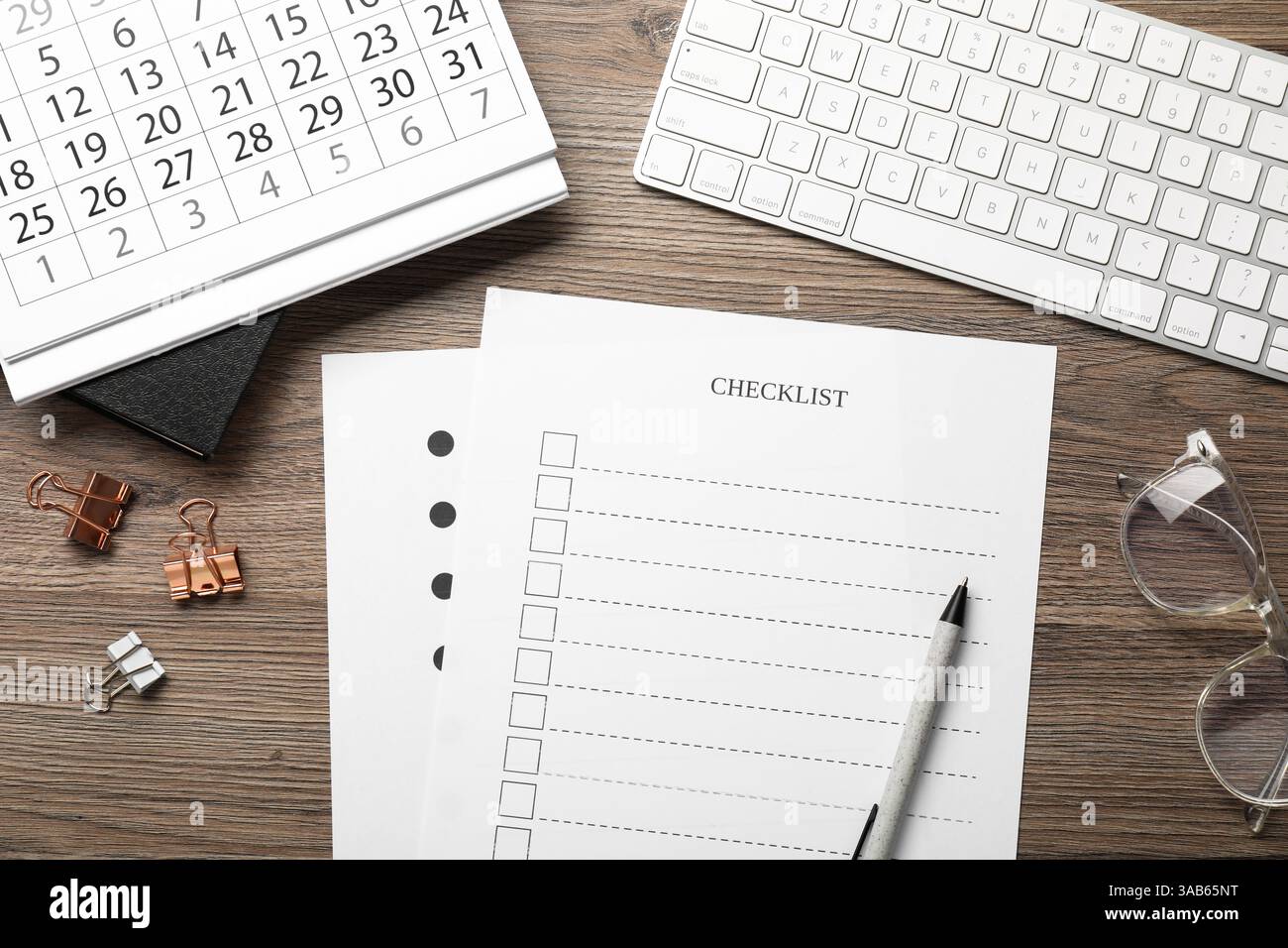 Checklist, pen, calendar, glasses, paper clips and keyboard on wooden ...