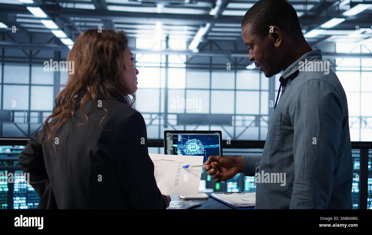 Data Center Team Reviewing Paperwork In Server Room Analyzing System Reports Using Ai On Tablet