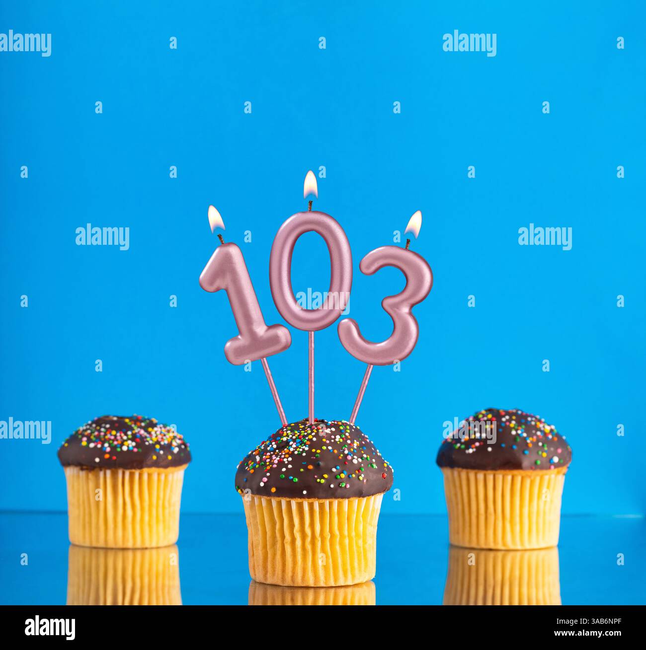 Three birthday cupcakes with number 103 candle - Blue background Stock ...