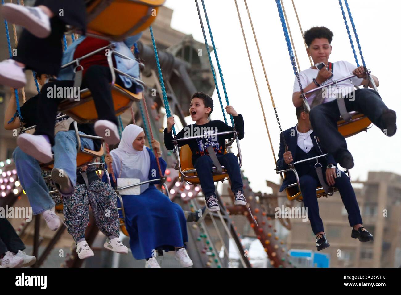 Cairo, Egypt. 1st Apr, 2025. People ride on a swing carousel at an ...
