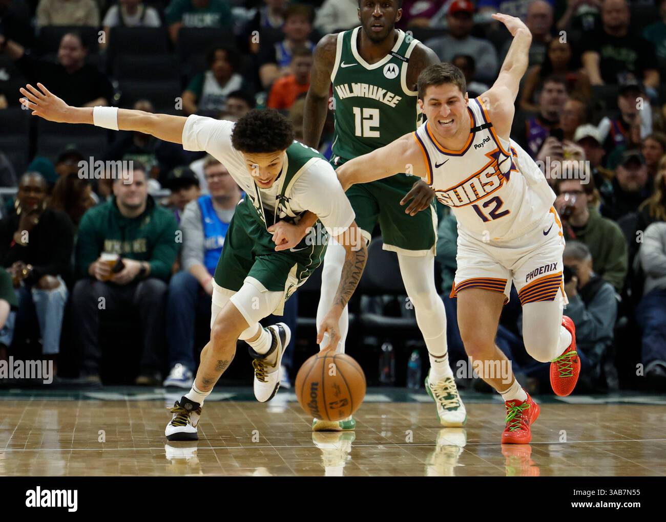 Milwaukee Bucks' Ryan Rollins, left and Phoenix Suns' Collin Gillespie (12) reach for a loose ...