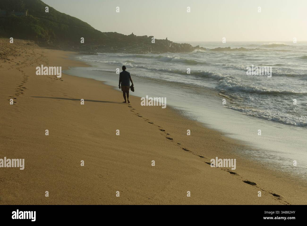 Silhouette of single man walking on beautiful beach in early morning ...