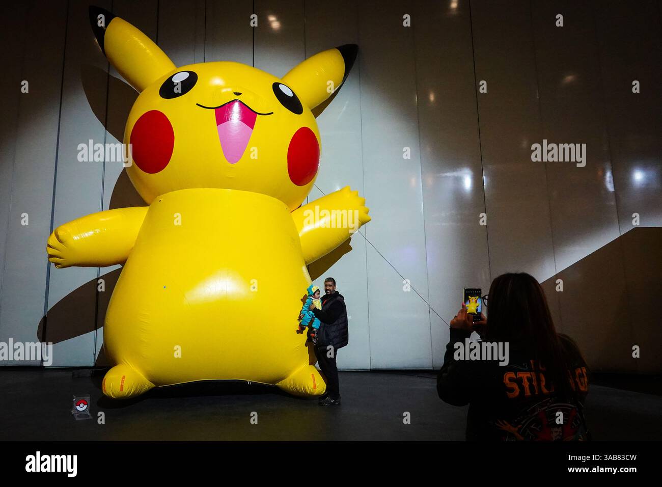 Visitors are seen gesturing in front of the Pikachu decoration. London ...