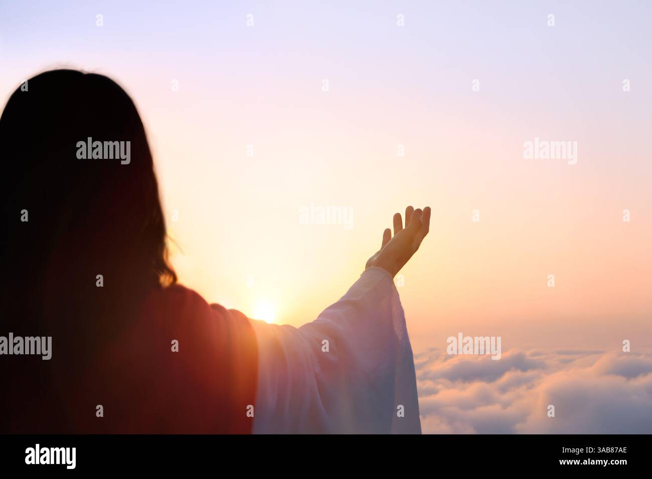 Jesus praying to God with arms raised towards bright light heaven sky ...