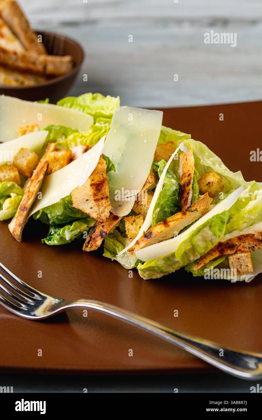 Chicken Caesar salad served on a porcelain plate with crusty bread ...
