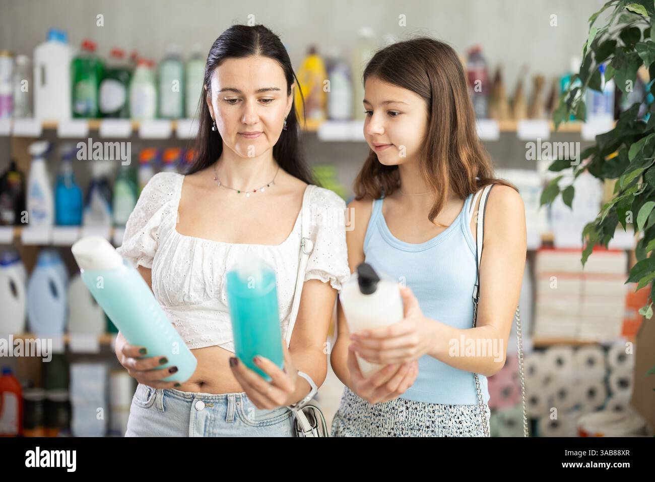 Woman with teen daughter choosing shampoo in hygiene store Stock Photo ...