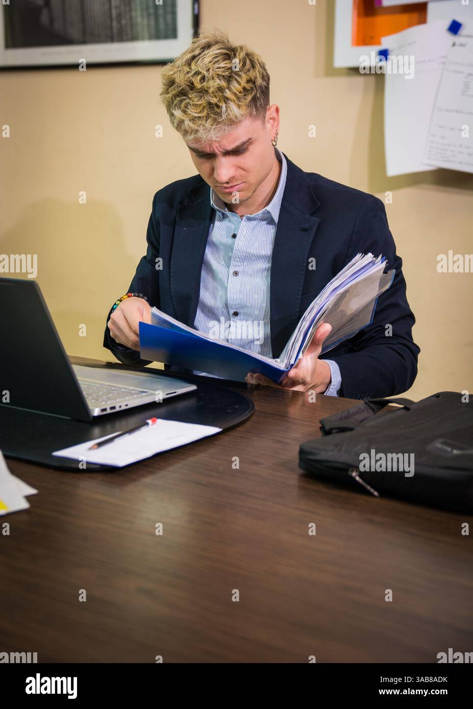 A young man with blond hair and blue eyes concentrates on reviewing a ...