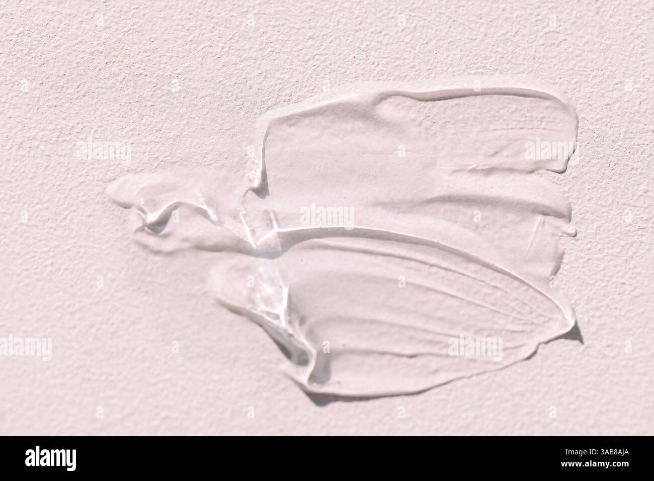 The texture of the cream on a light background. Translucent serum is ...