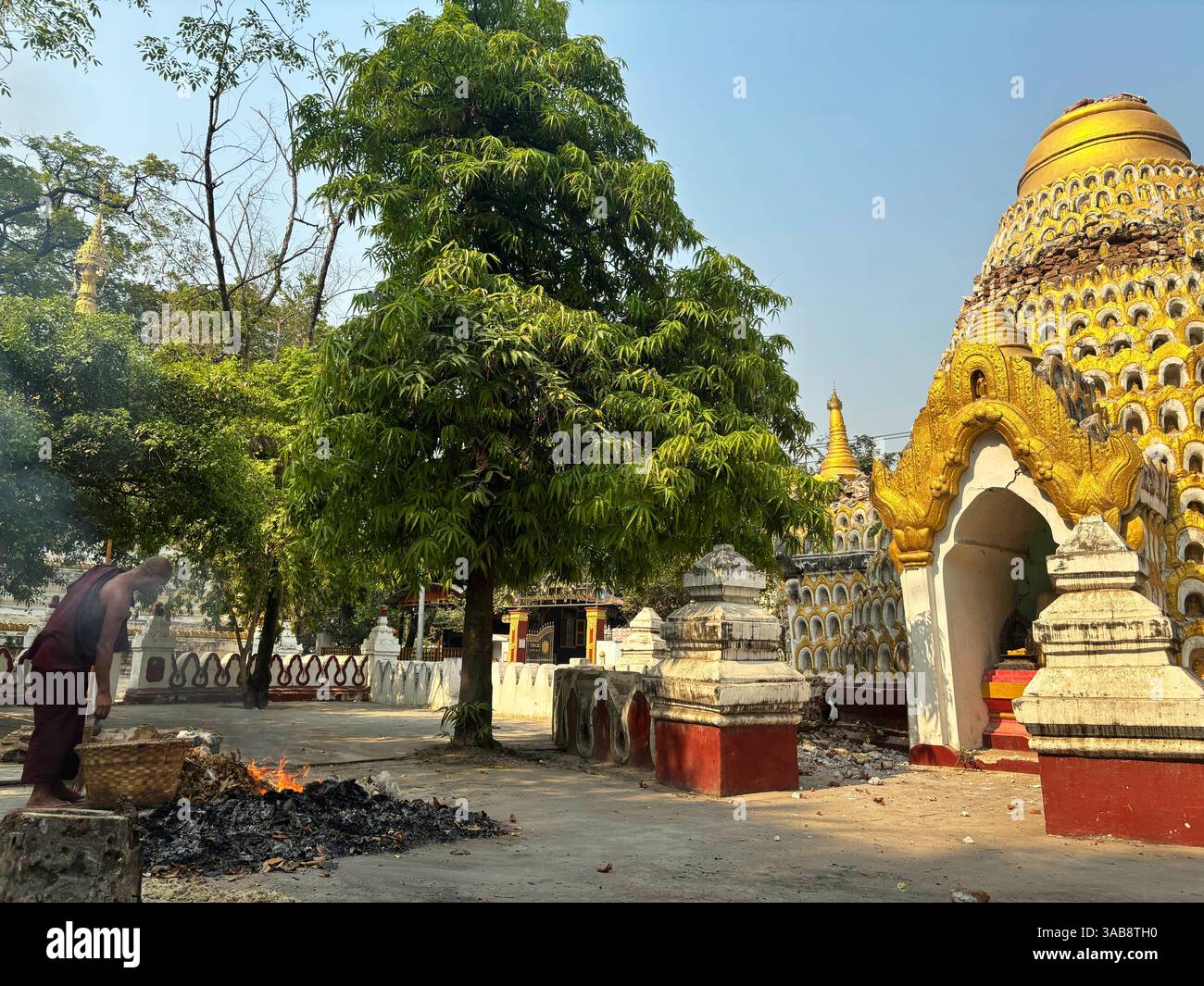 A Buddhist monk set dry-leaves fire near a damaged pagoda in the ...