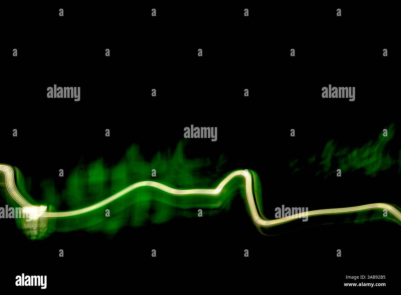 Vivid green light trails weave through a dark space, creating an ...