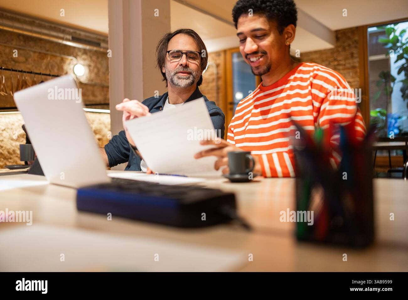 Two colleagues collaborating in a stylish coworking space, sharing ...