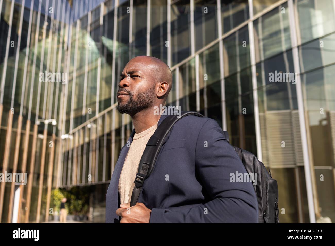 A confident cuban man with a backpack stands outside a modern office ...