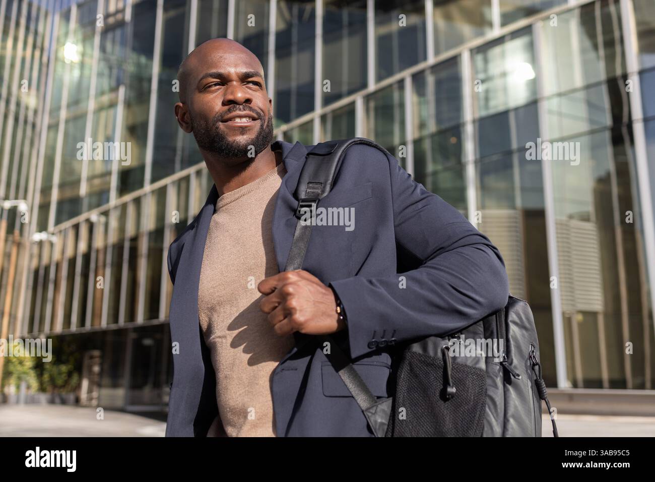 A confident cuban man in a blazer and sweater, carrying a backpack ...
