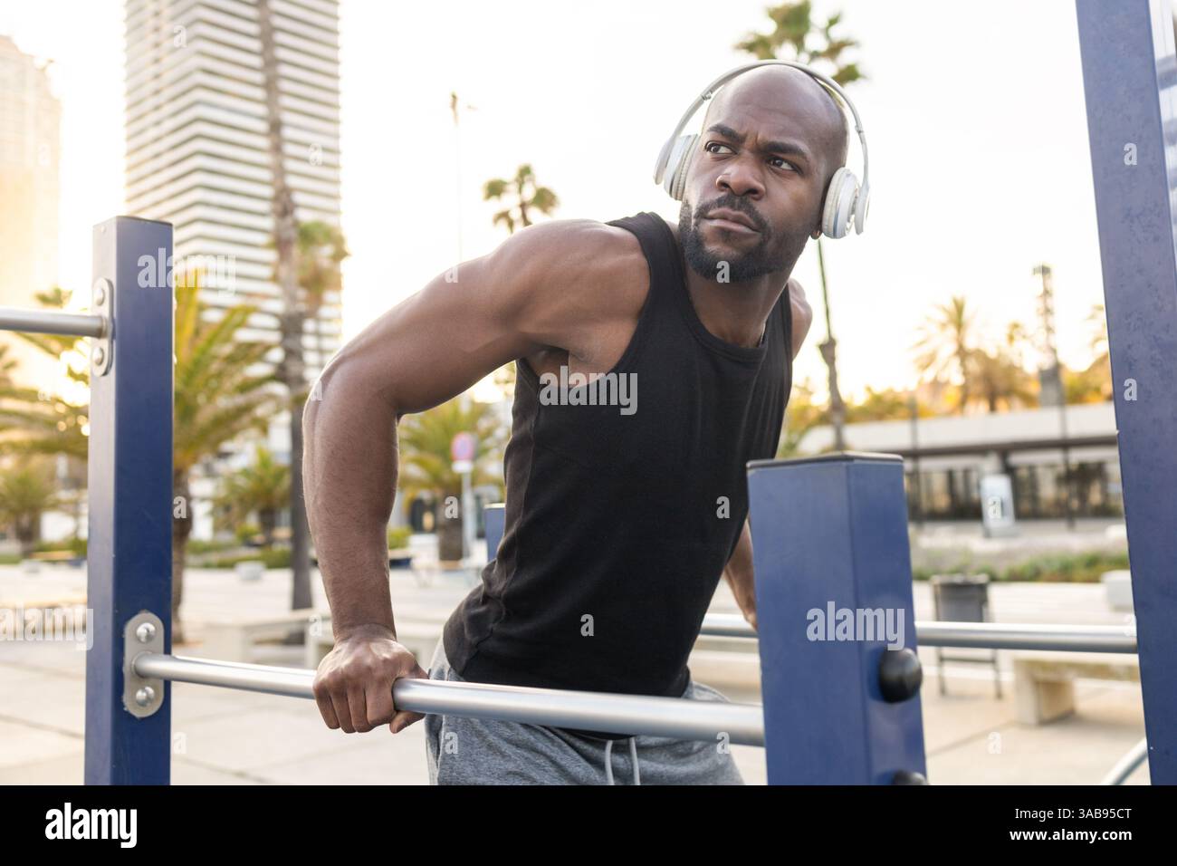 Cuban man in a black tank top works out at an outdoor fitness park ...